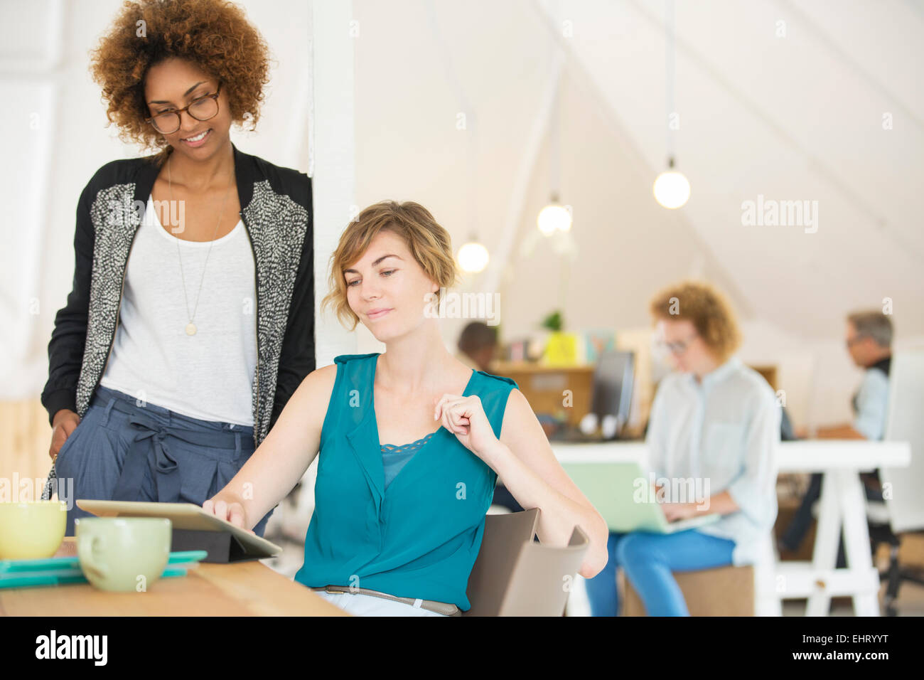 Two office workers talking at desk using tablet Stock Photo - Alamy