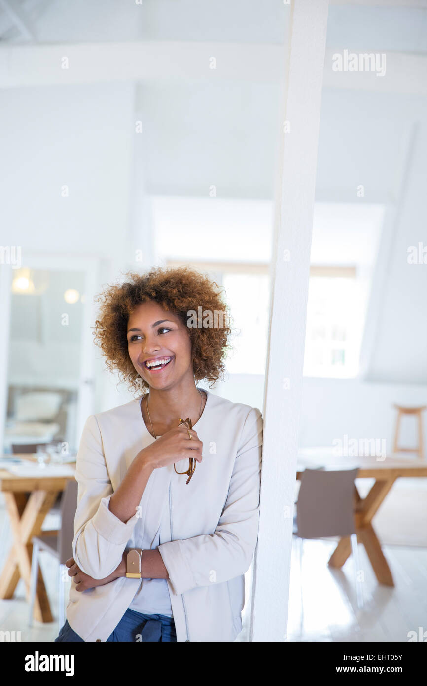 Portrait of woman leaning on column in office and smiling Stock Photo ...