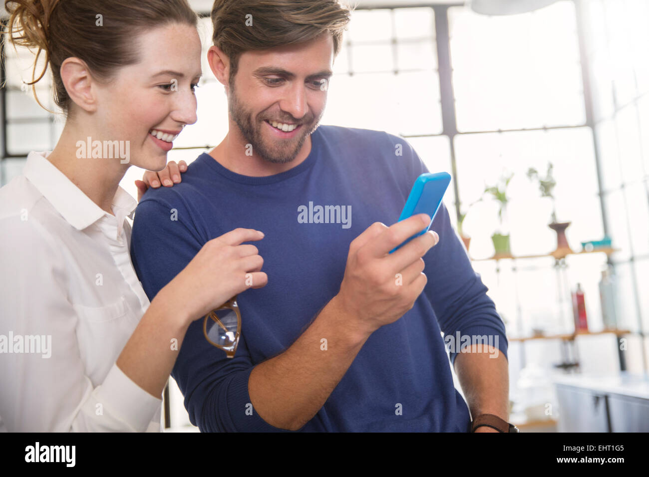 Two young people looking at mobile phone and smiling Stock Photo - Alamy