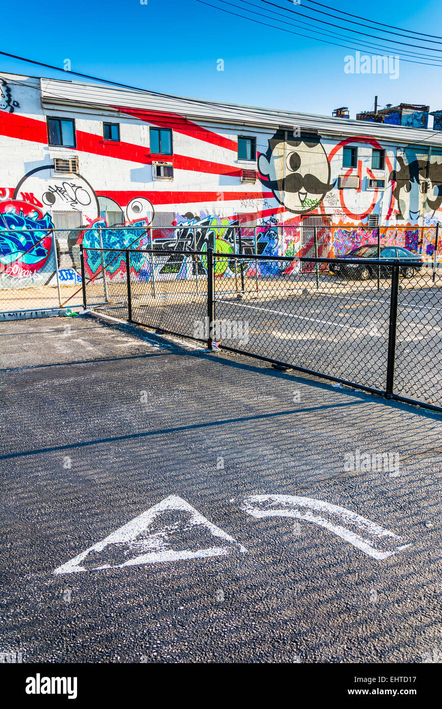 Arrow on pavement in a parking lot and graffiti on a building in ...