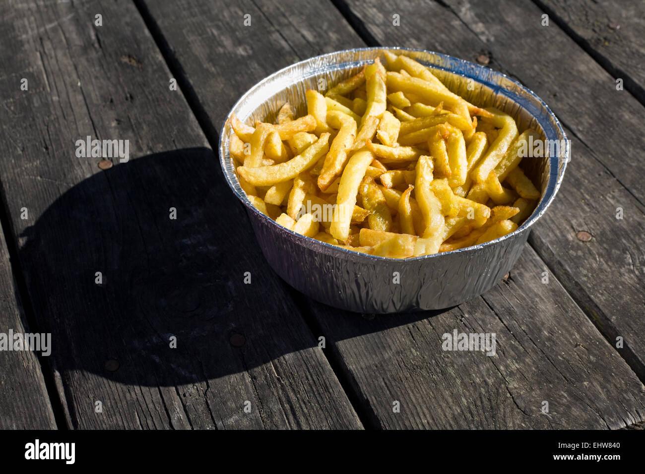 French fries in aluminum foil tray. Served over old wooden picnic table ...