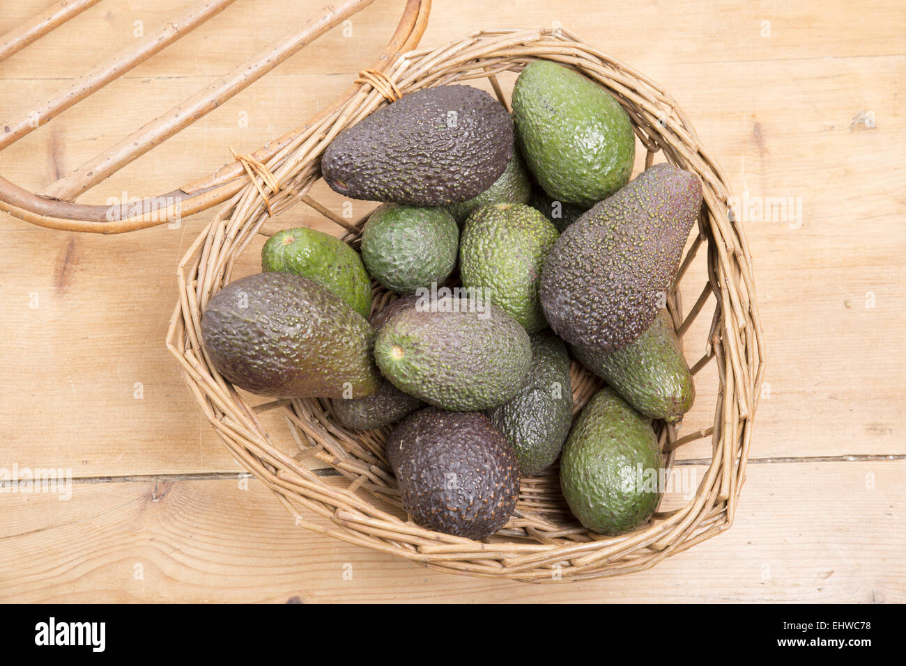 avocados presented in a small basket in heart shape on wooden table ...