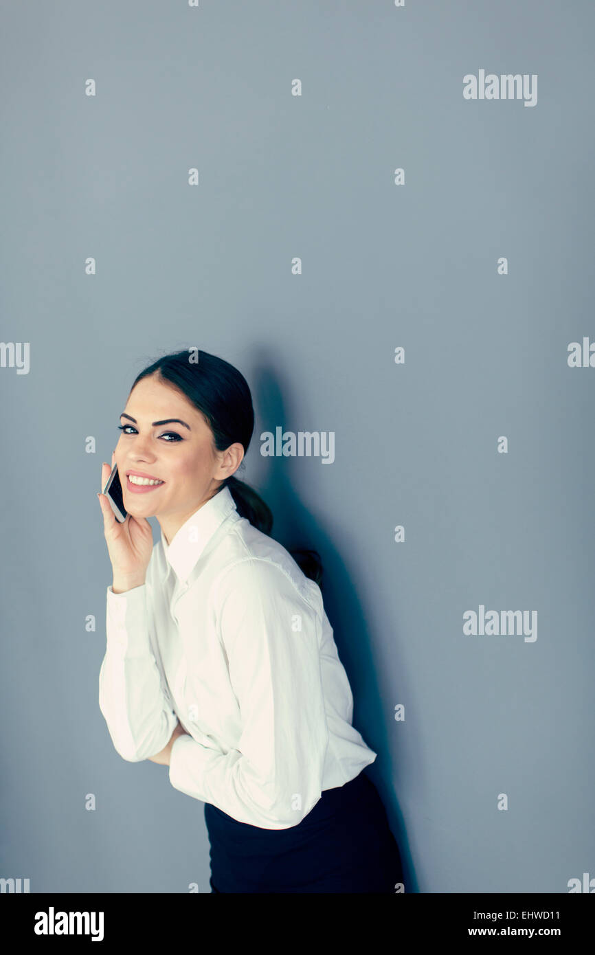 Young woman with mobile phone by the wall Stock Photo - Alamy