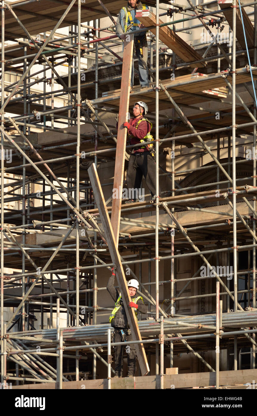 London, England, UK. Construction workers passing long planks up ...
