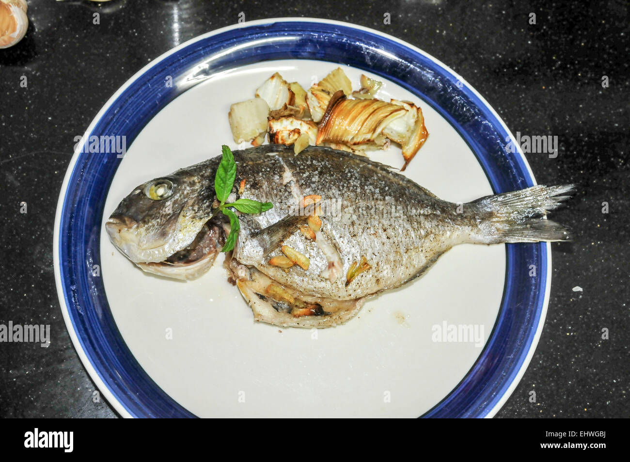 a plate with a Grilled fish with garlic Stock Photo - Alamy