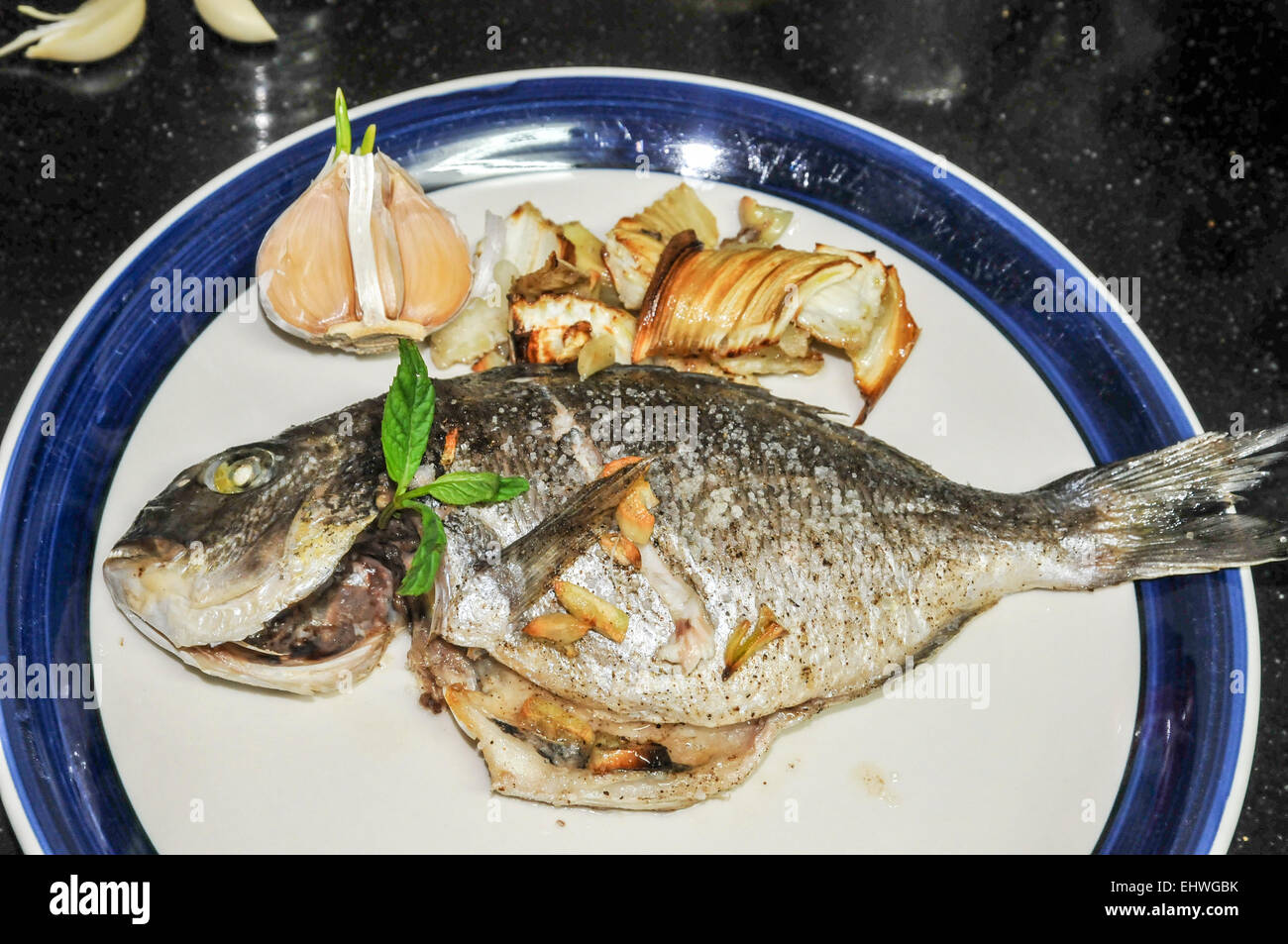 a plate with a Grilled fish with garlic Stock Photo - Alamy
