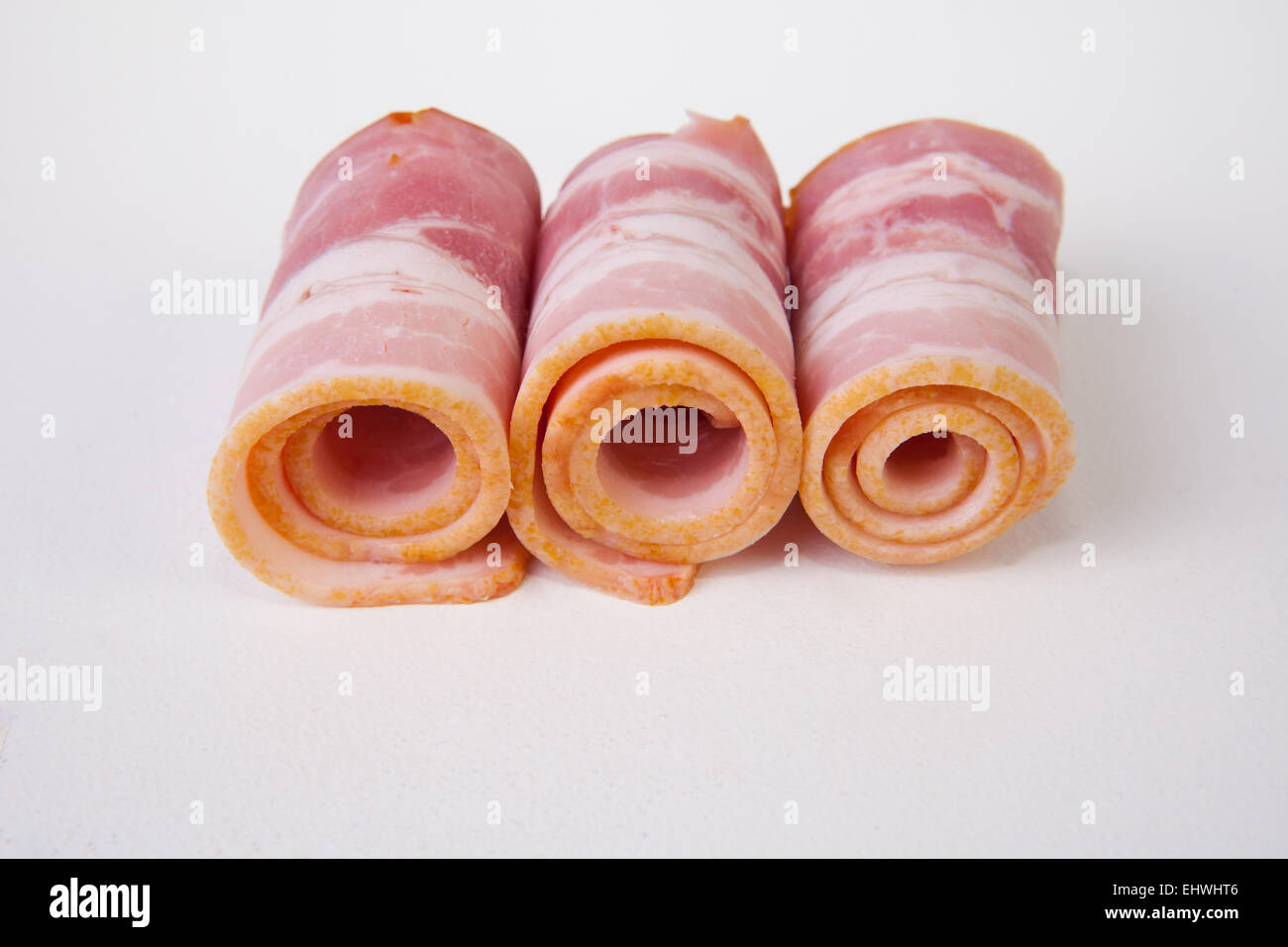 Three rolled raw bacon slices isolated on white background Stock Photo ...