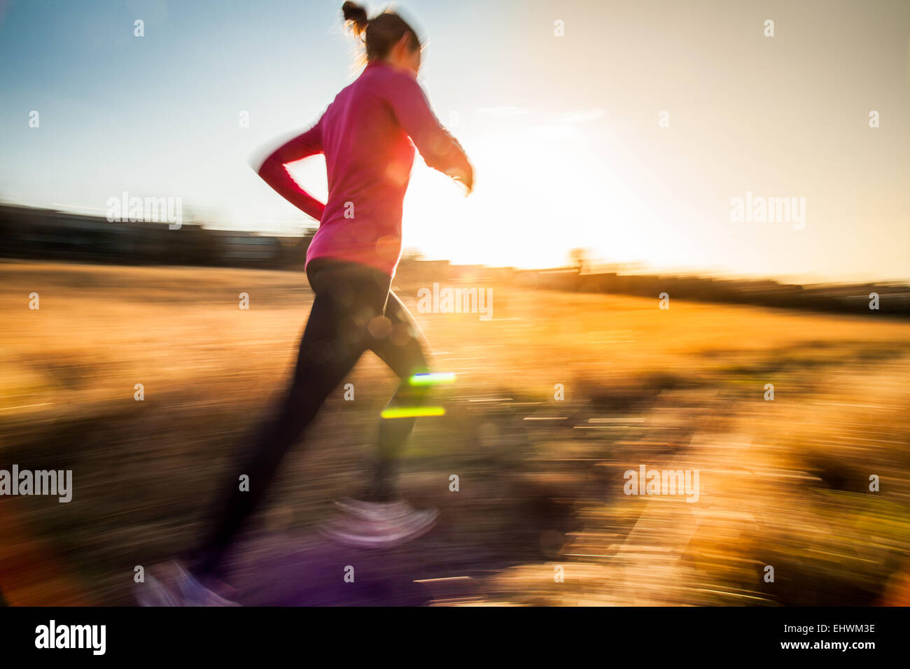 Young woman running outdoors on a lovely sunny winter/fall day (motion ...