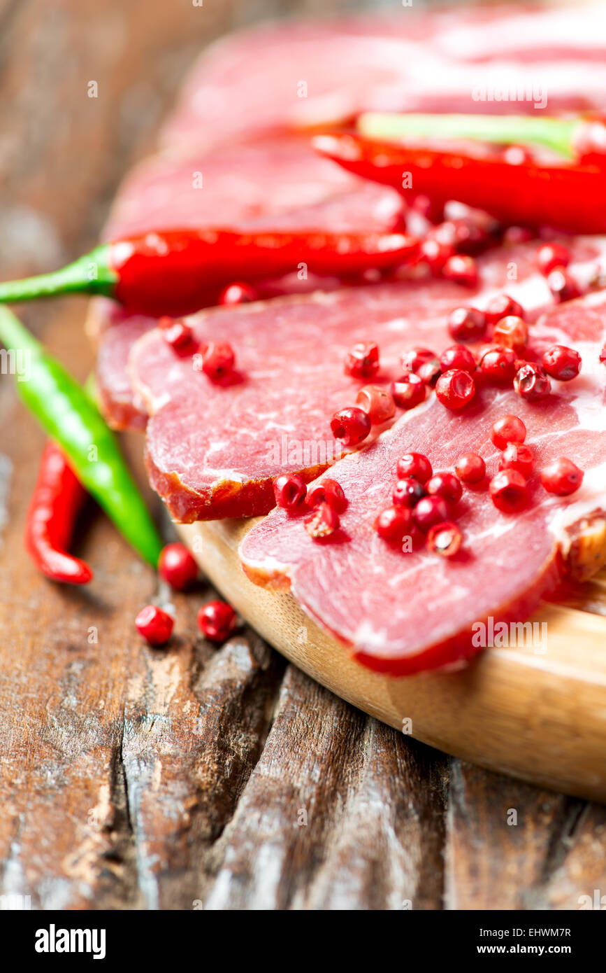 Cured meat with red chilli pepper on wooden table Stock Photo - Alamy