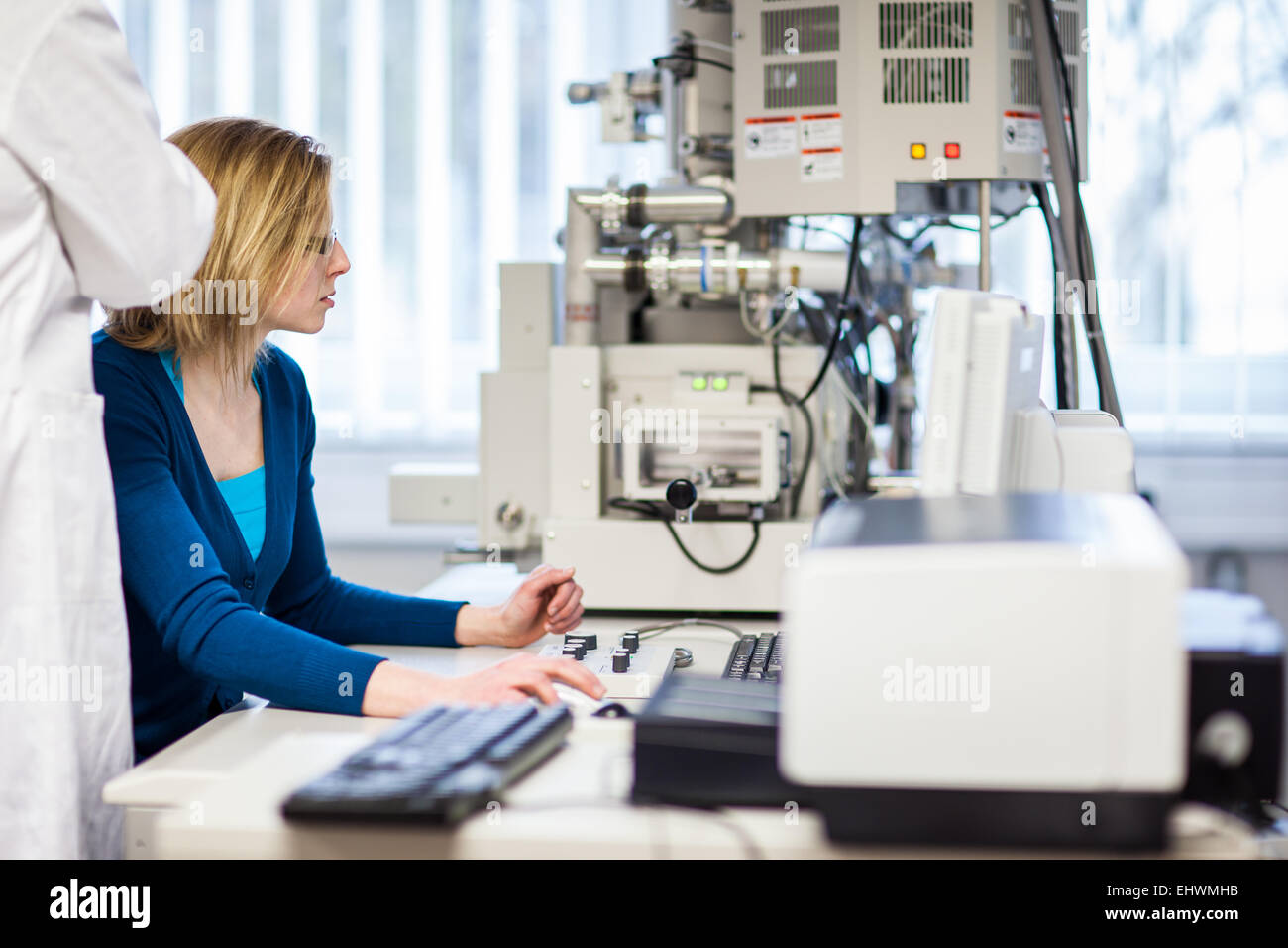 Pretty, female researcher using a microscope in a lab, doing research ...