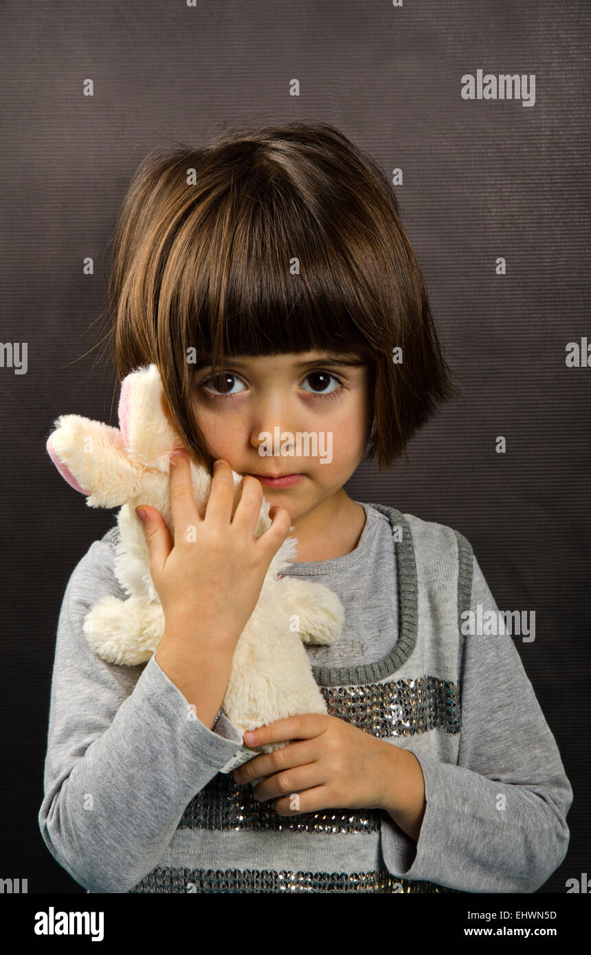 A FOUR YEARS OLD GIRL HOLDING A TOY RABBIT LOOKING PERTURBED Stock ...
