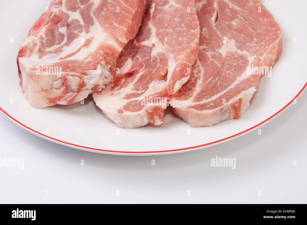 Middle rib chops of pork over plate. Isolated on white Stock Photo - Alamy