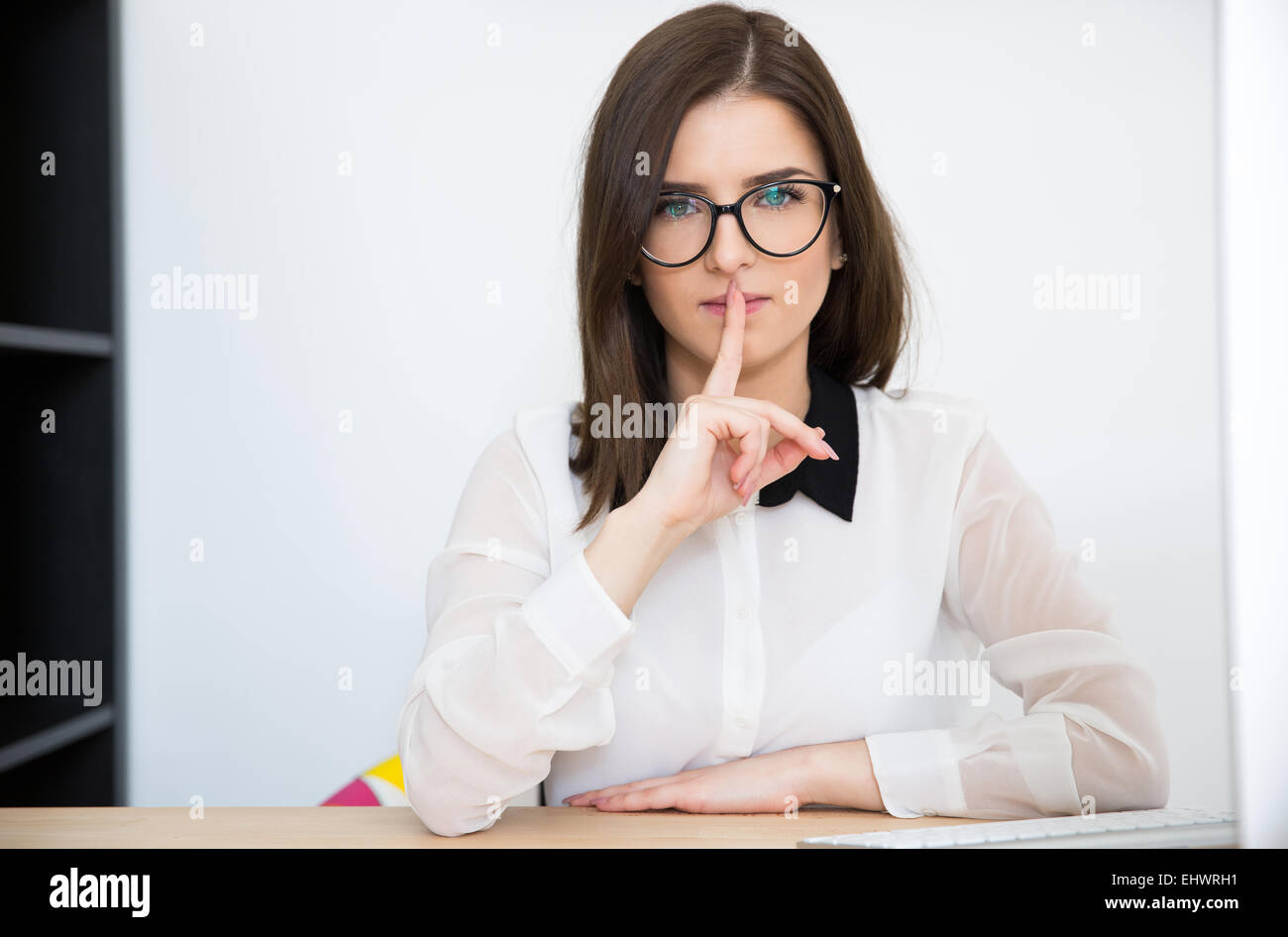 Young businesswoman sitting at the table with finger over lips Stock ...