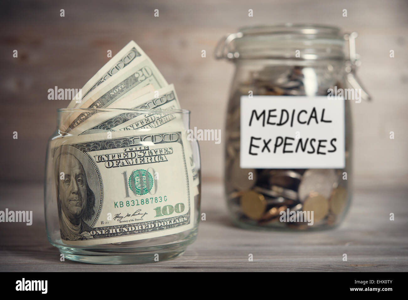 Dollars and coins in glass jar with medical expenses label, financial ...