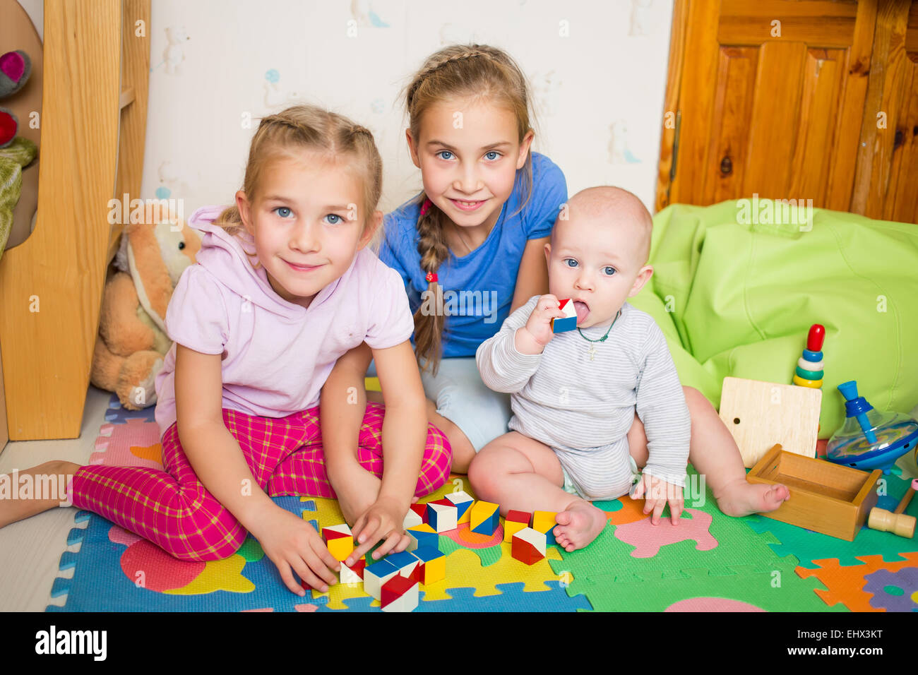 Happy kids playing with little brother in the room Stock Photo - Alamy