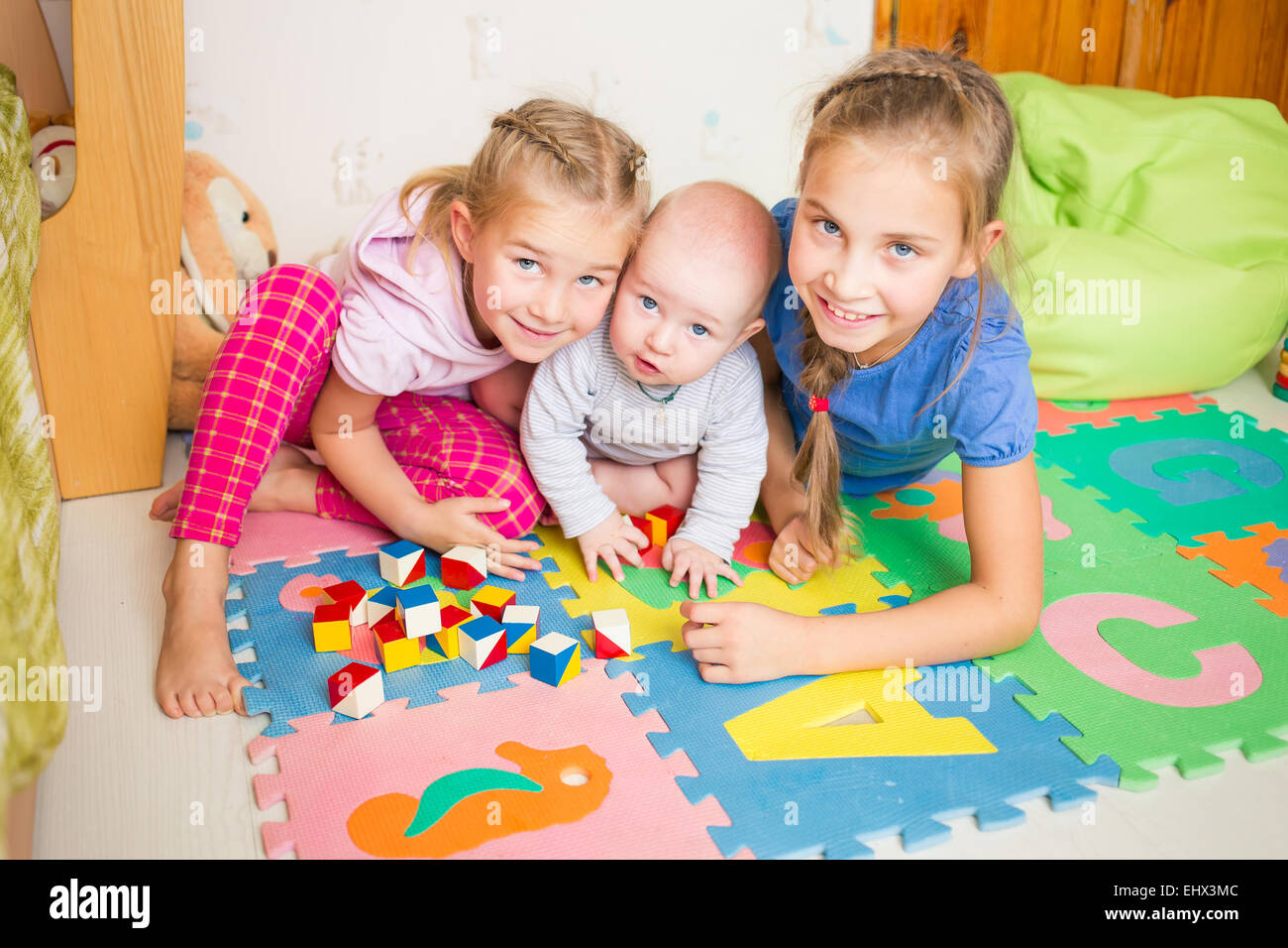 Happy kids playing with little brother in the room Stock Photo - Alamy