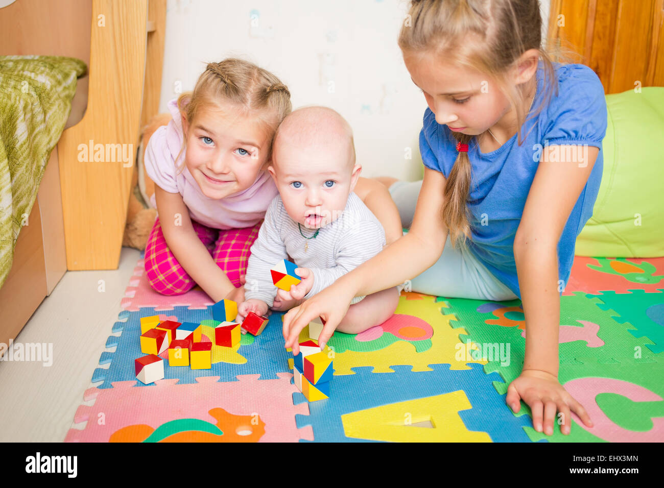 Happy kids playing with little brother in the room Stock Photo - Alamy