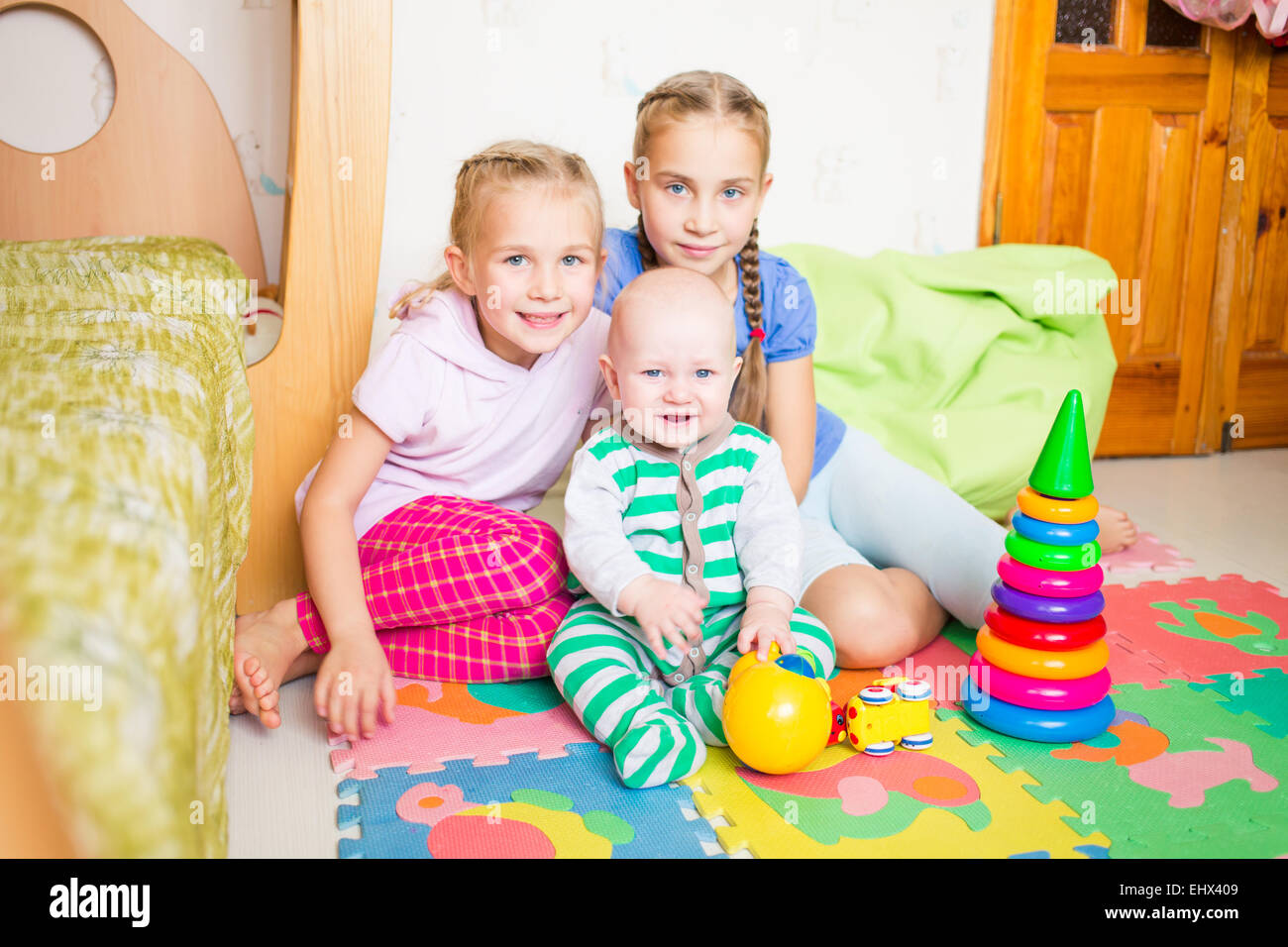 Happy kids playing with little brother in the room Stock Photo - Alamy