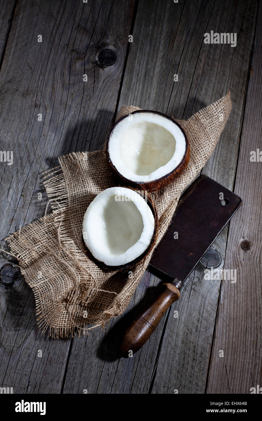 Split coconut on hessian and old cleaver Stock Photo - Alamy
