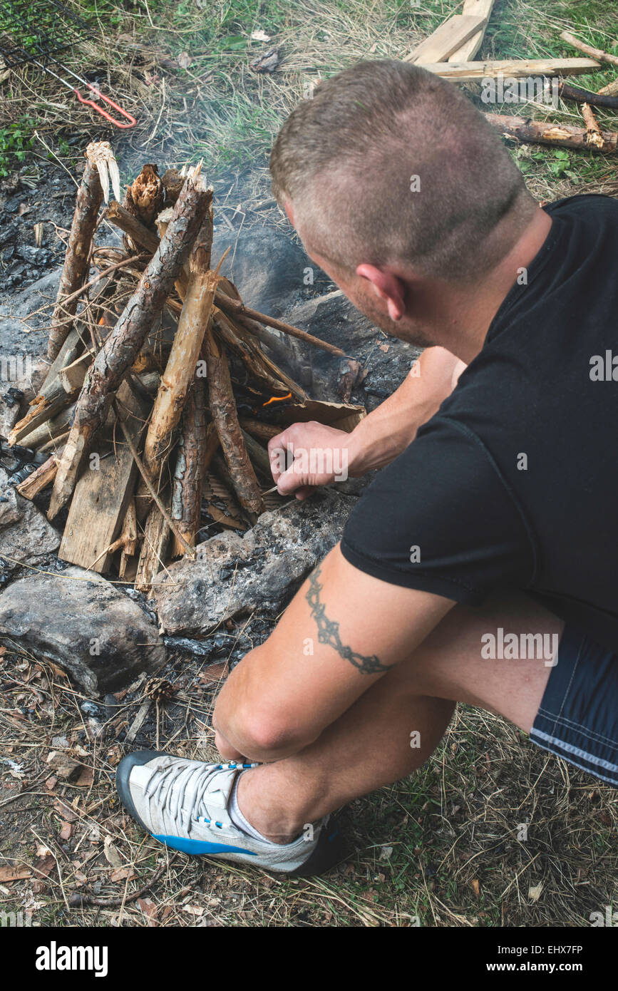 Man lighting a fire on a meadow Stock Photo - Alamy