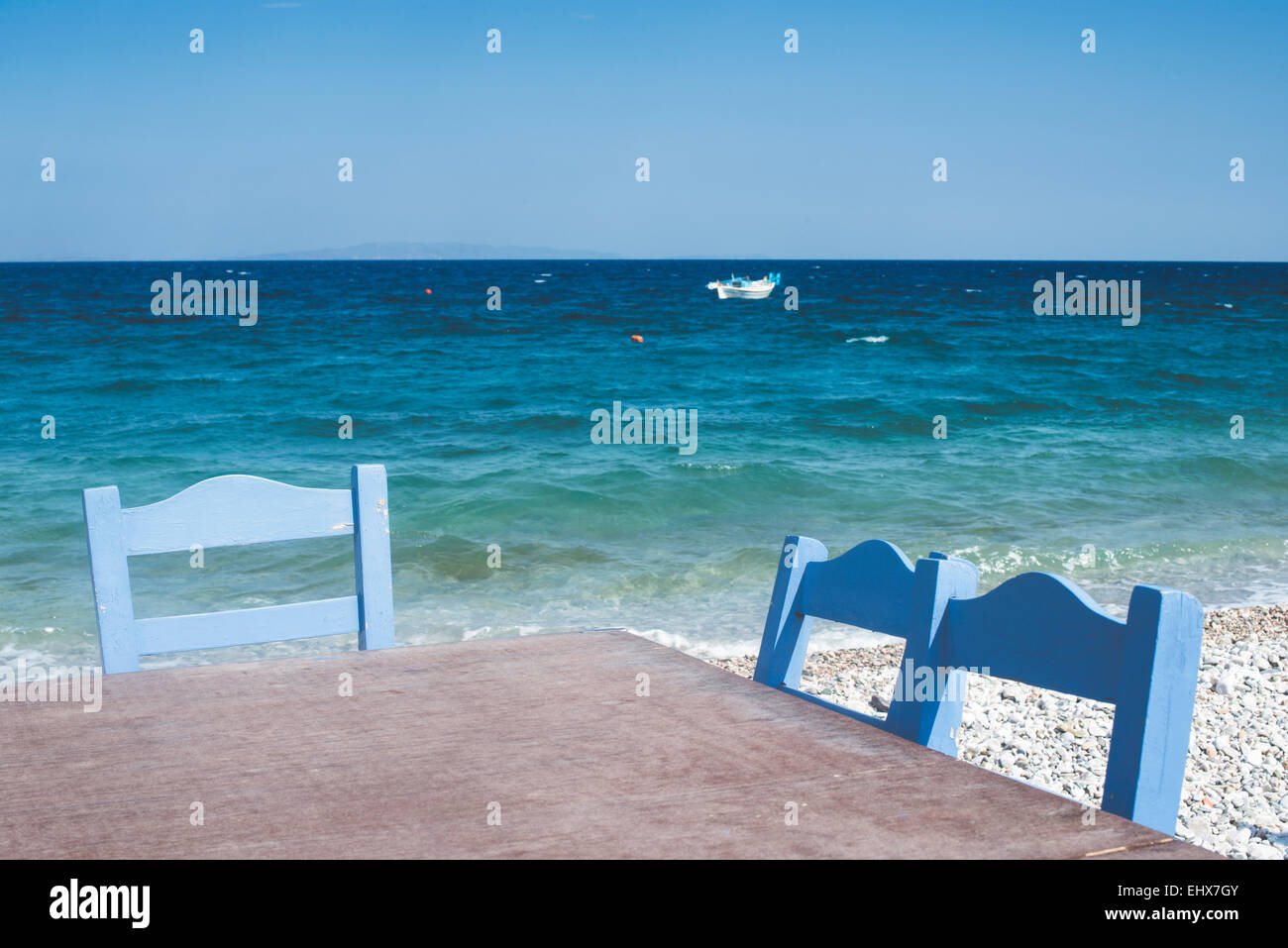 Greece, table and three chairs at seashore Stock Photo - Alamy
