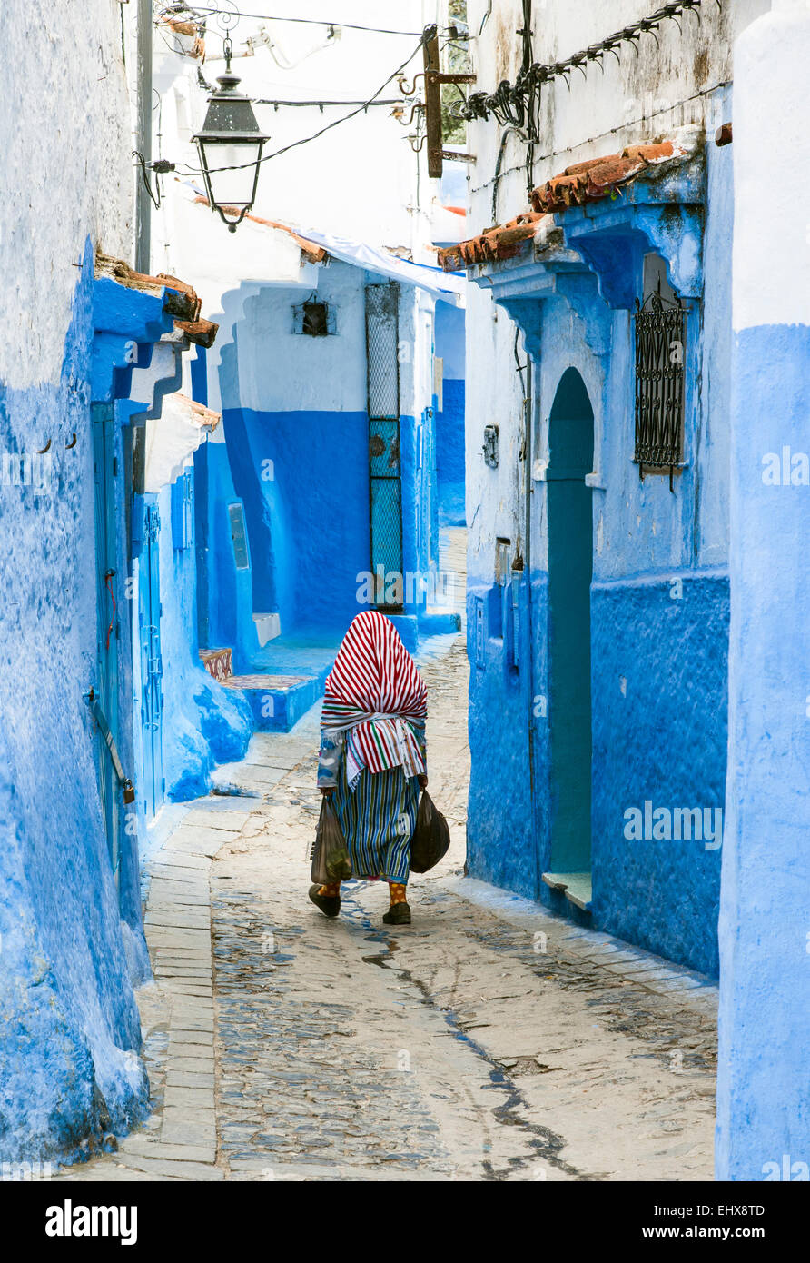 A local woman in traditional clothing walking the blue-washed streets ...