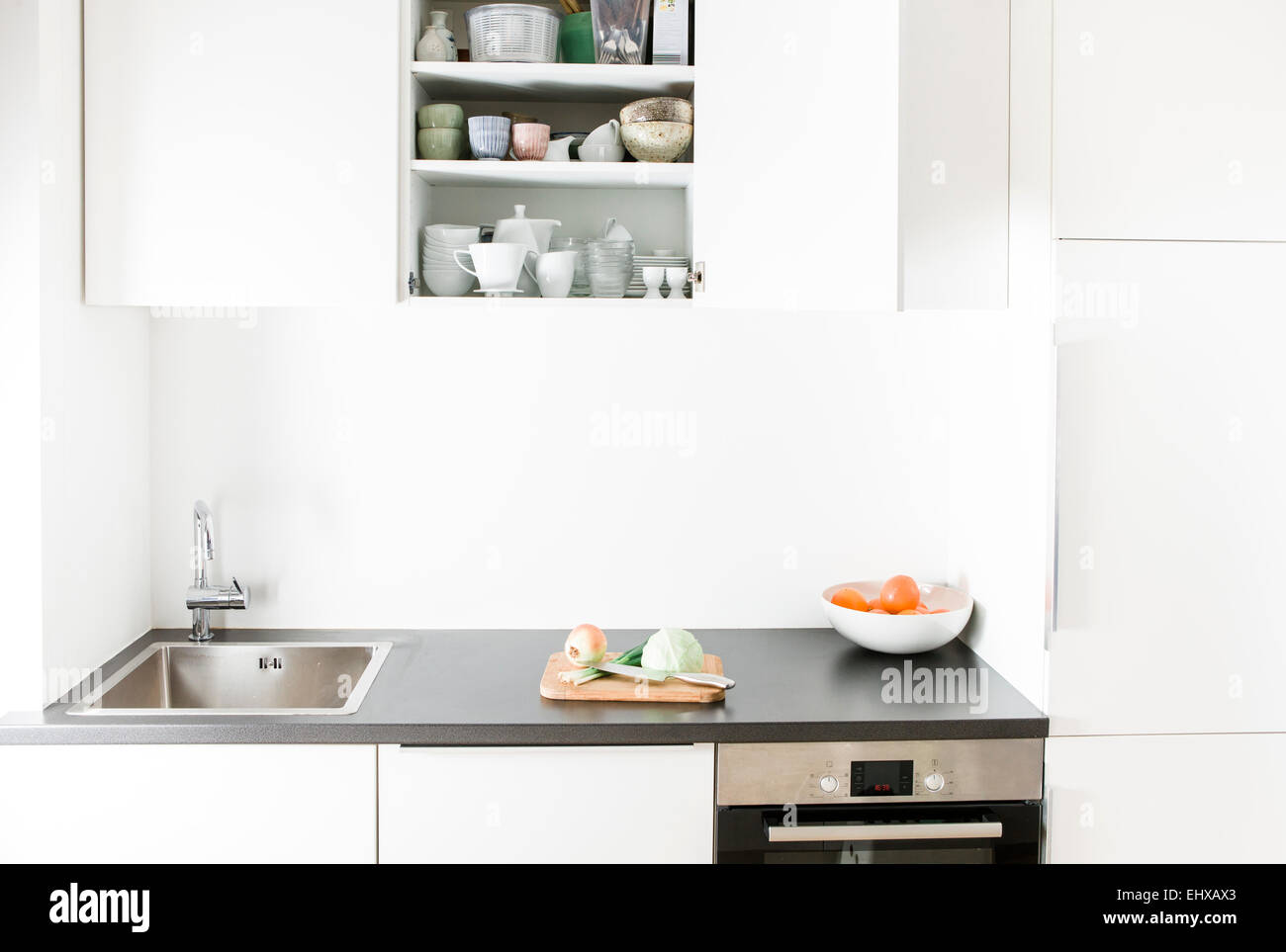 Modern kitchen, chopping board with vegetables, open cupboard Stock ...