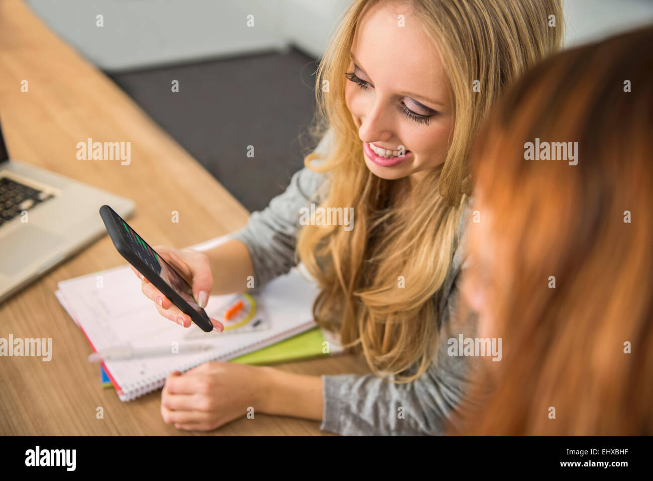 Happy girl friends text messaging with smartphone, Munich, Bavaria ...