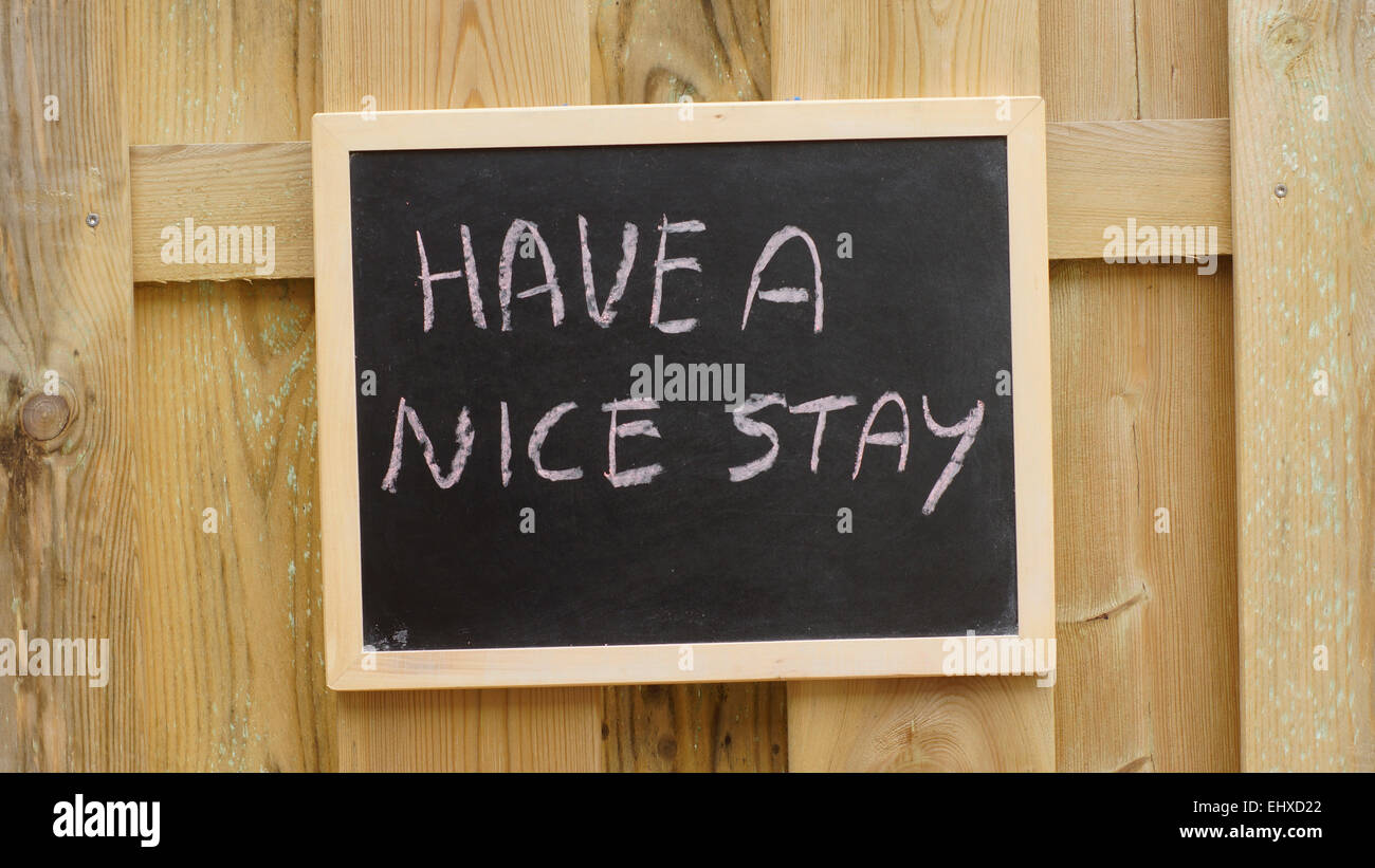 Have a nice stay written at a chalkboard hanging at a wooden wall Stock ...