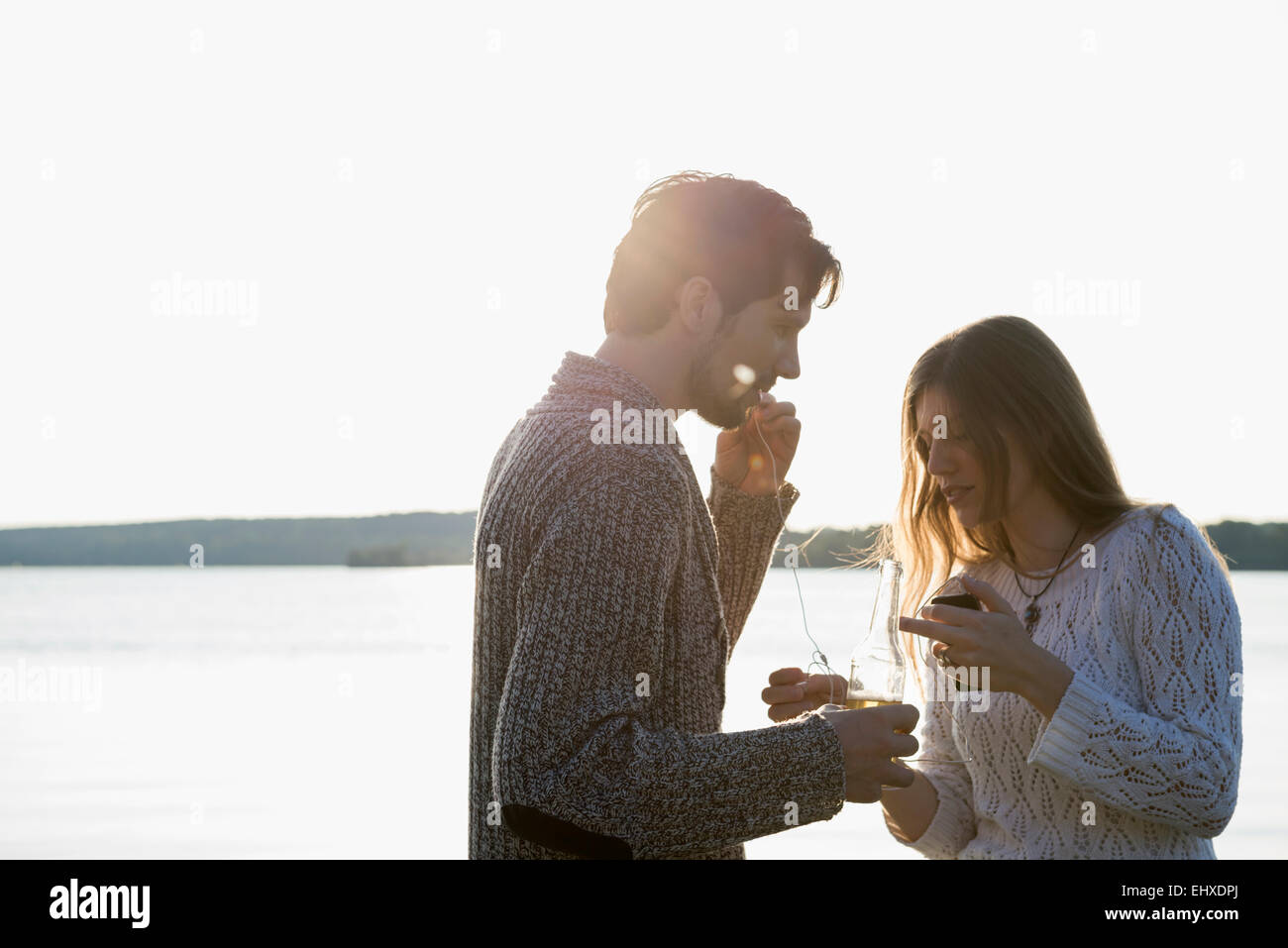 Couple sharing cell phone music drinking beer Stock Photo - Alamy