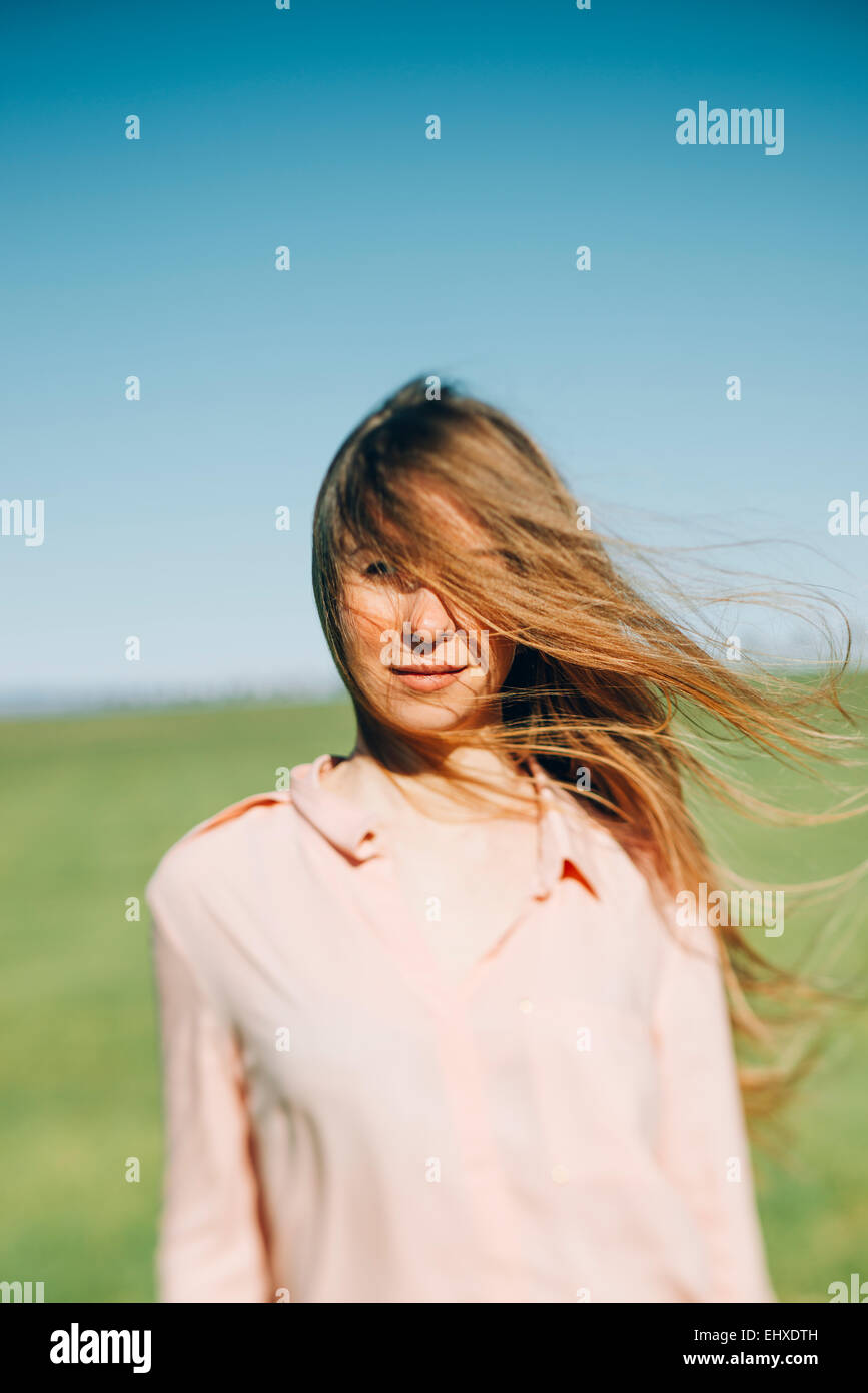 Portrait of young woman with windswept long hair Stock Photo - Alamy