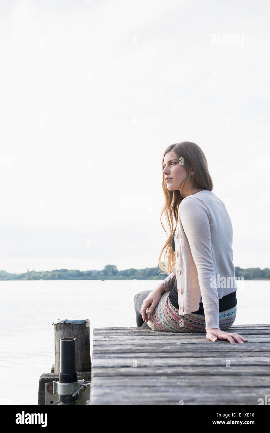 Portrait young woman sitting jetty thoughtful Stock Photo - Alamy