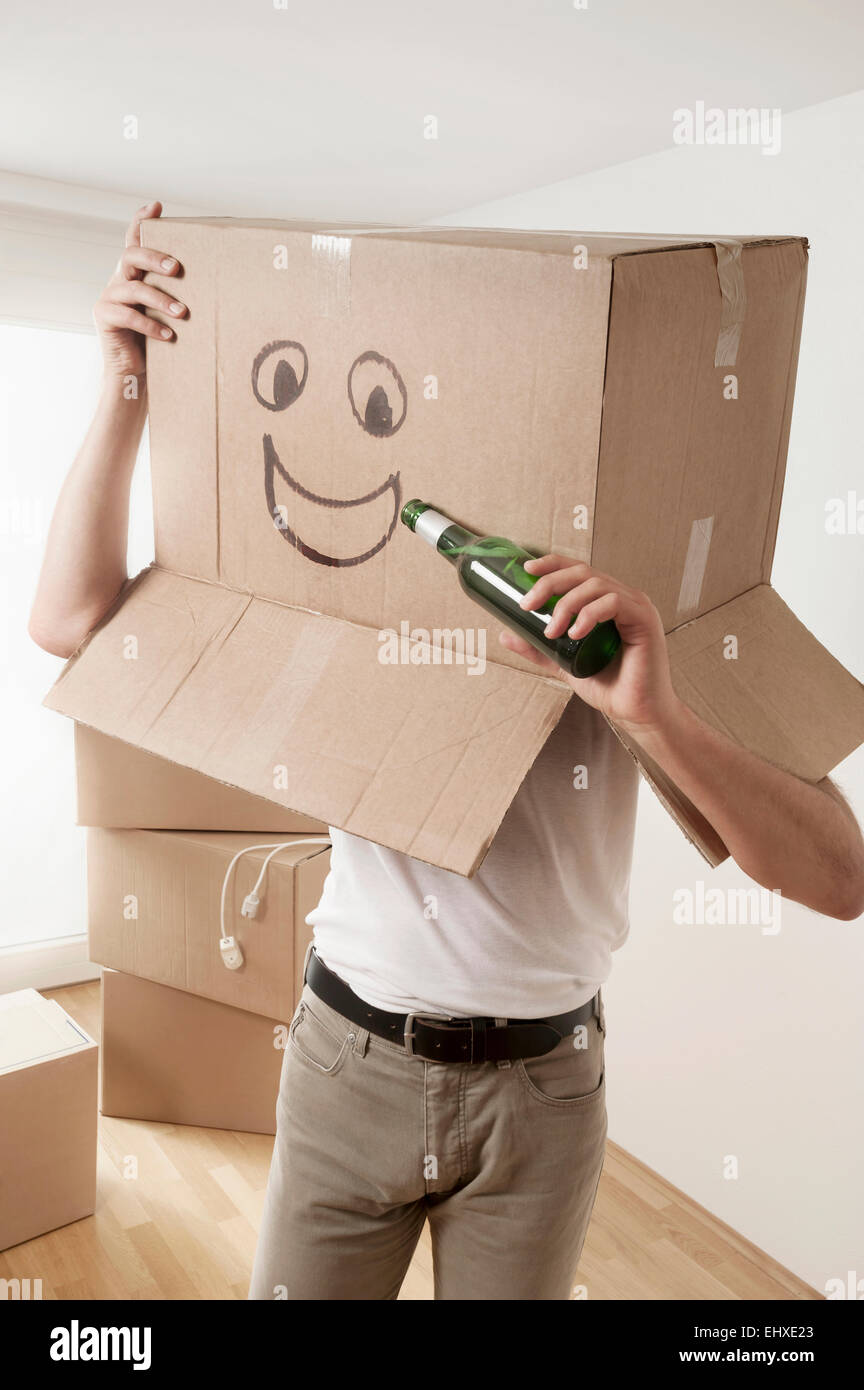 Man wearing happy face moving box over head and pretending to drink ...