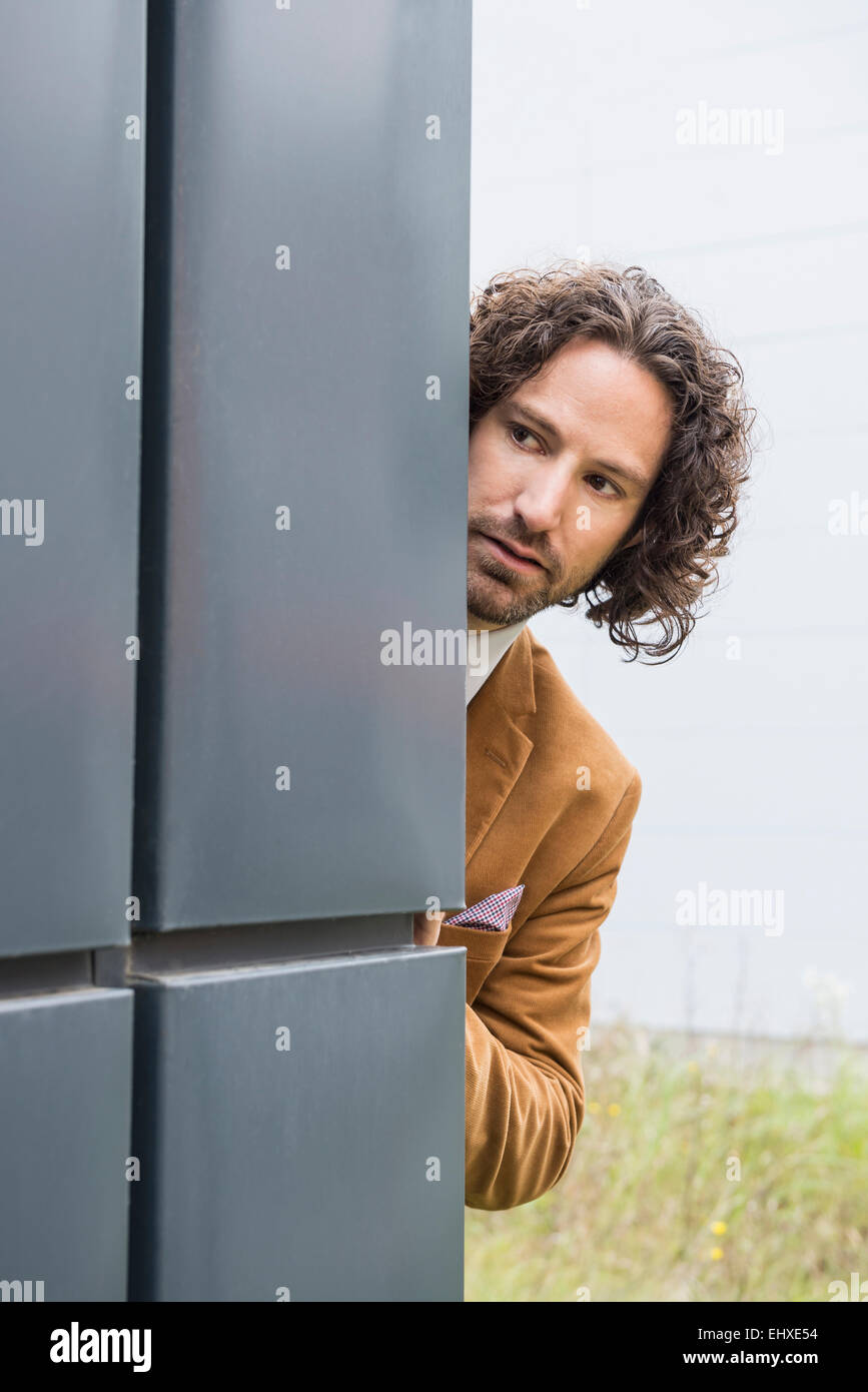 Inquisitive man hiding looking snoopy suspicious Stock Photo - Alamy