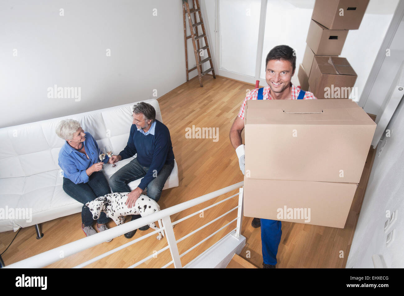 Removal man moving cardboard box upstairs and senior couple celebrating ...