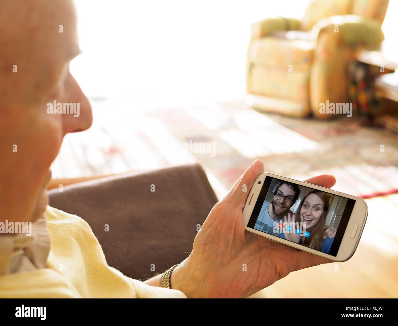 Grandfather videoconferencing with grandchildren via smartphone Stock ...