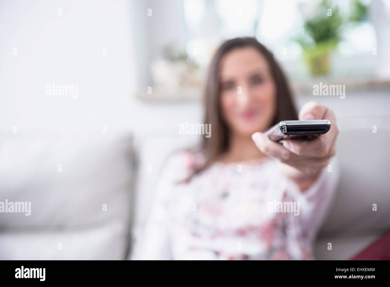 Woman changing television channel with remote control, Munich, Bavaria ...