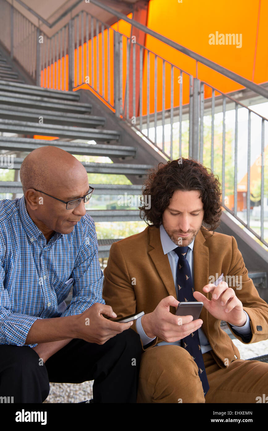 Holding cell phone talking two men steps sitting Stock Photo - Alamy