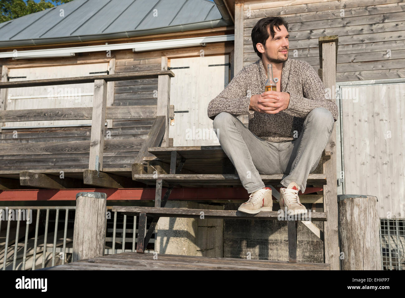 Man sitting drinking beer wooden steps relaxing Stock Photo - Alamy