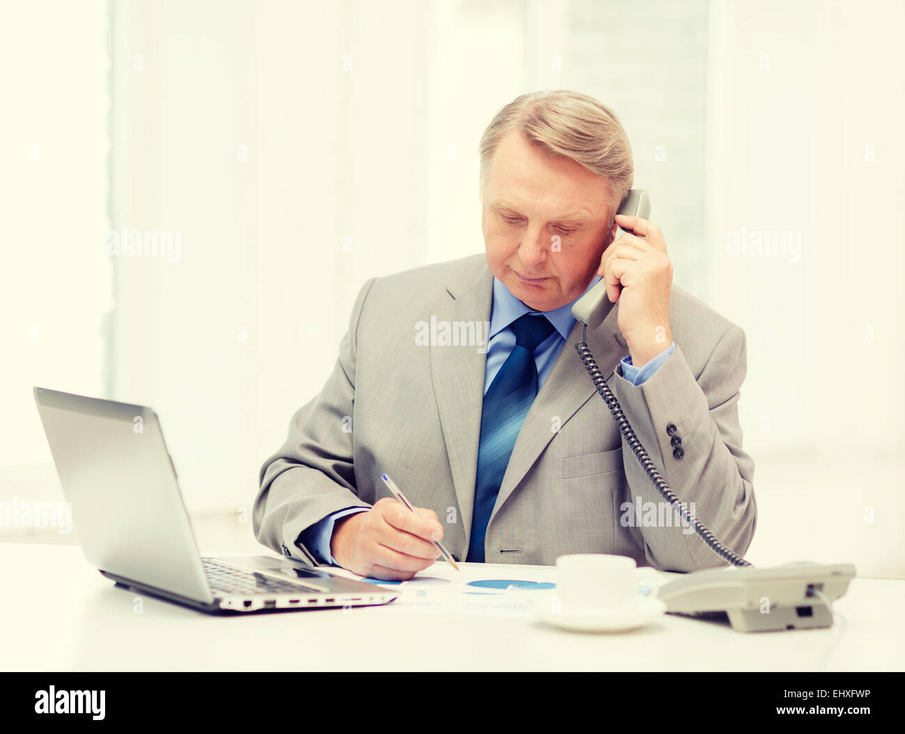 busy older businessman with laptop and telephone Stock Photo - Alamy