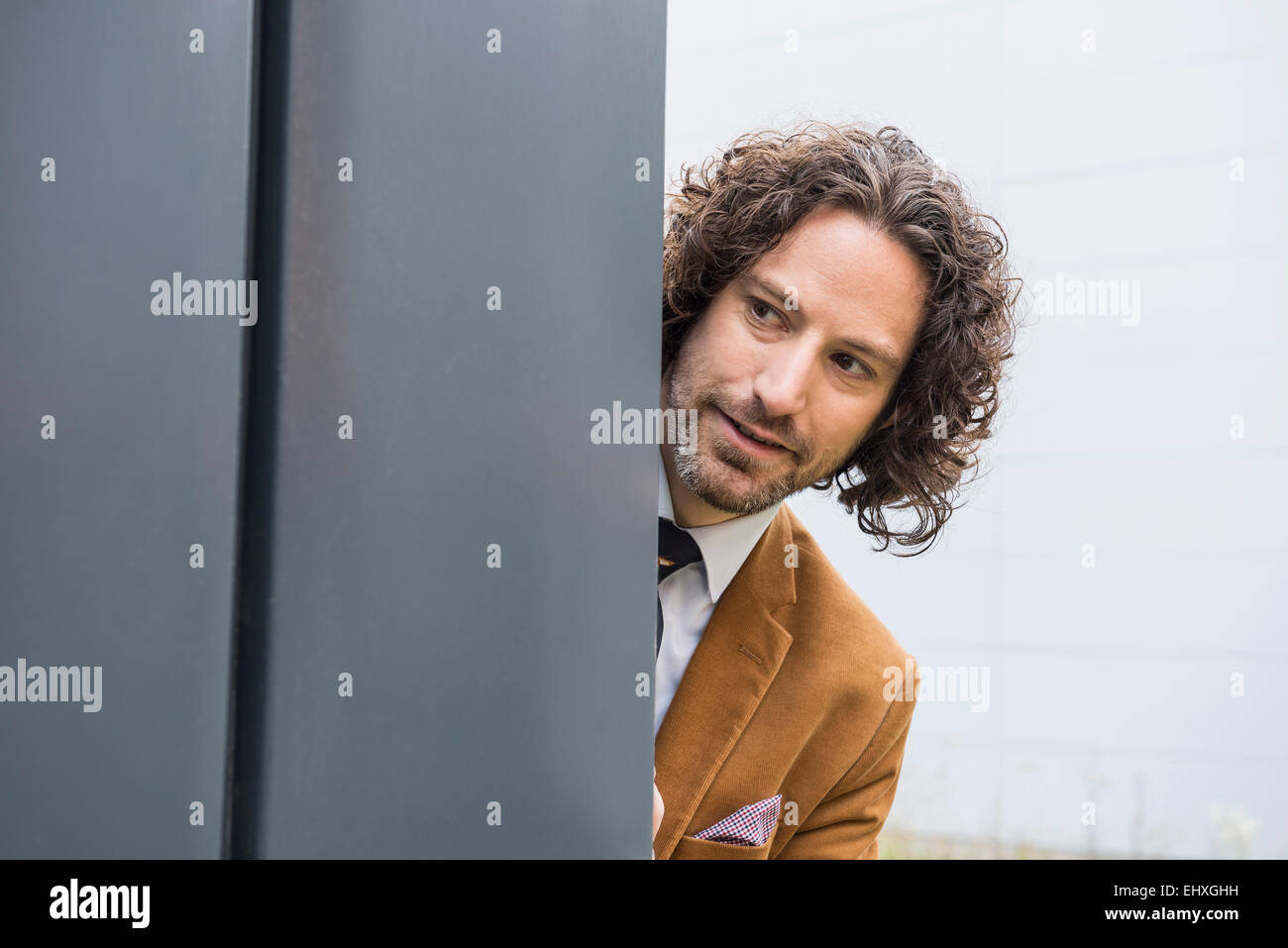 Portrait man close up wall curious looking hiding Stock Photo - Alamy