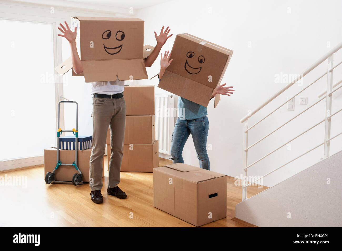 Couple wearing happy face moving boxes over heads and dancing, Bavaria ...