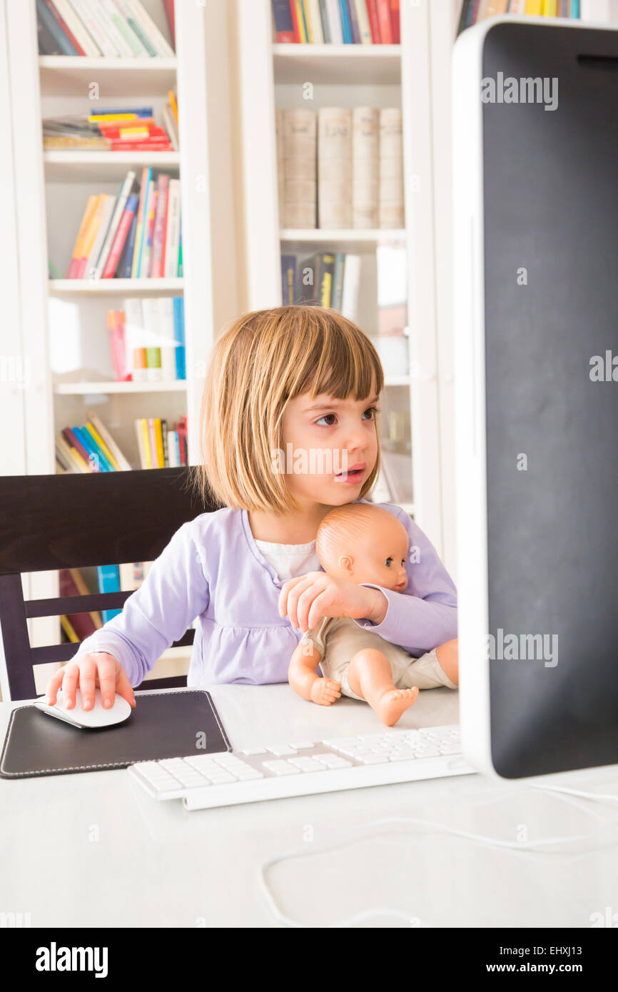 Portrait of little girl with doll spending time at computer Stock Photo ...