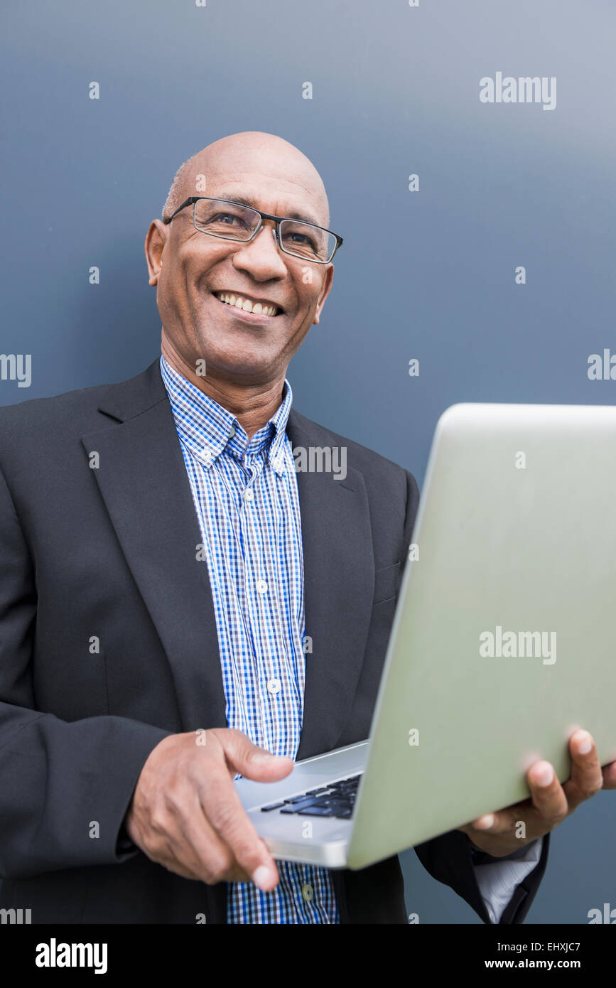 Happy African businessman holding laptop computer Stock Photo - Alamy