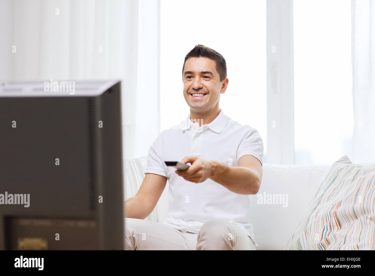 smiling man with remote control watching tv Stock Photo - Alamy