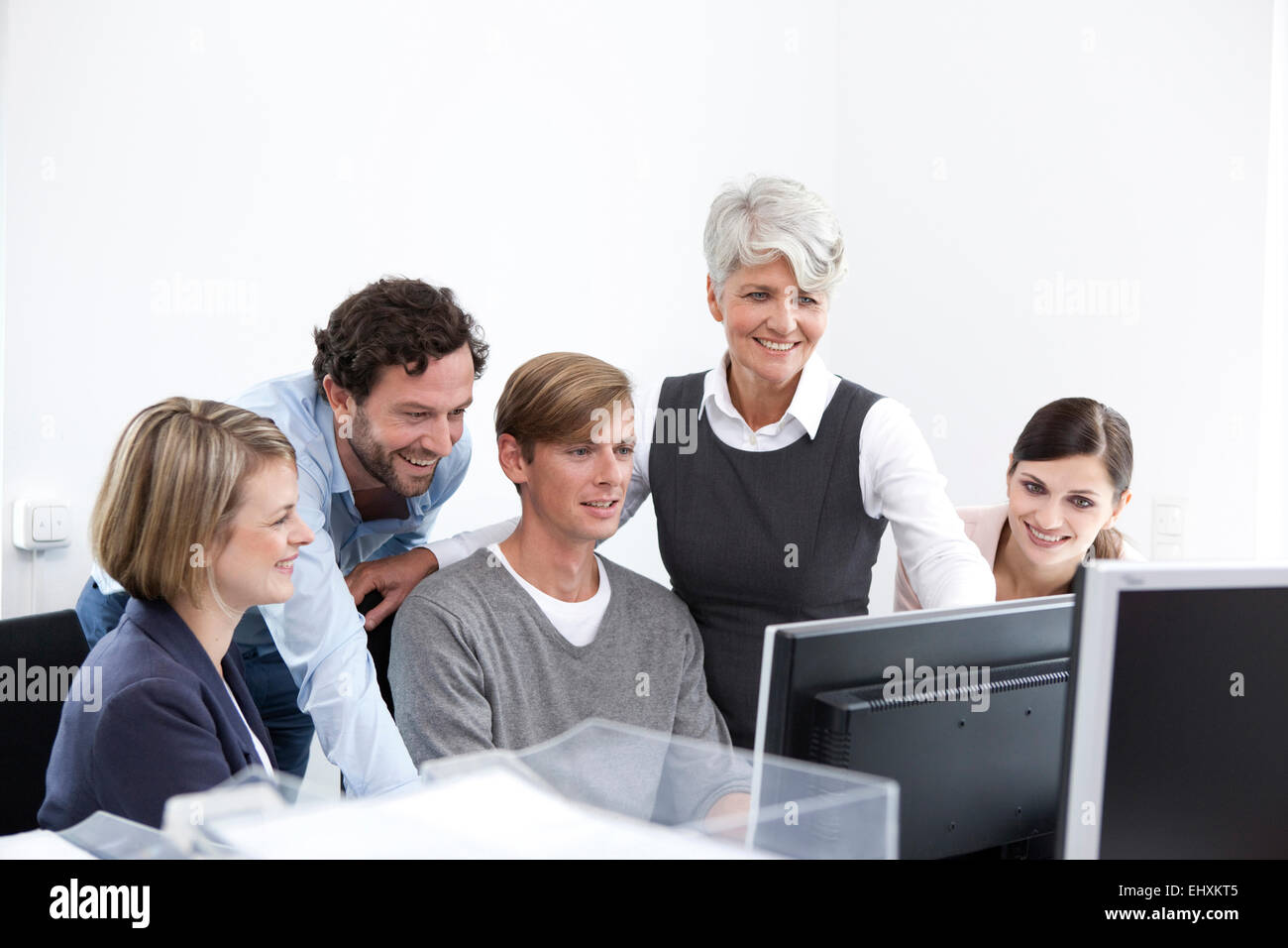 Smiling business team working on computer in office Stock Photo - Alamy