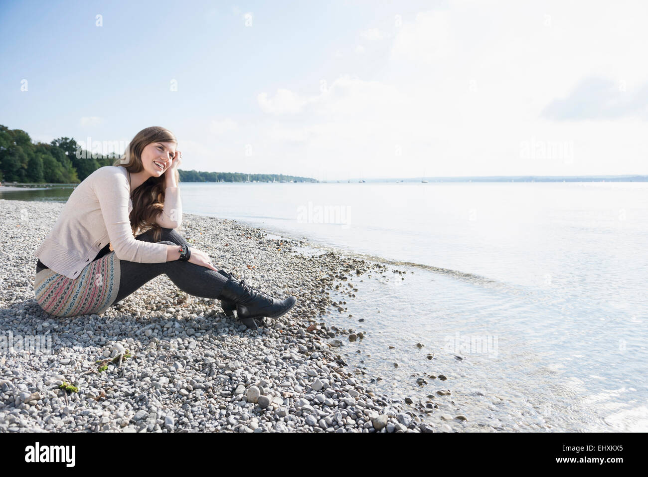 Pretty young woman sitting lake shore Stock Photo - Alamy