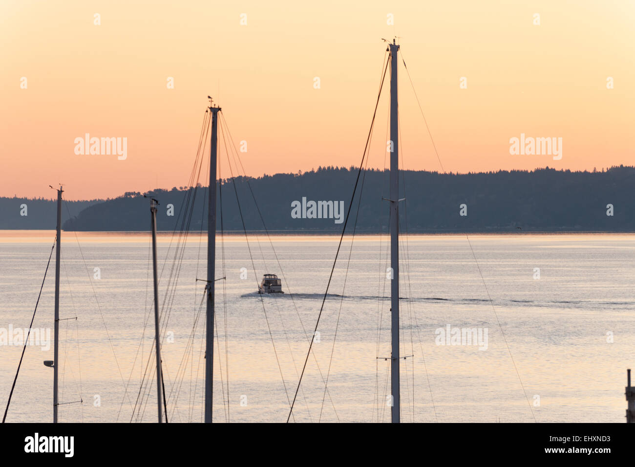 Power Boat Sets Out On An Evening Cruise with sailing boat masts in the ...