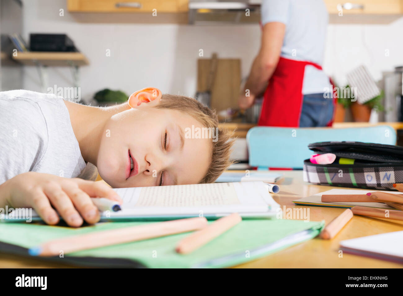 Boy sitting at kitchen table sleeping on his school book Stock Photo ...