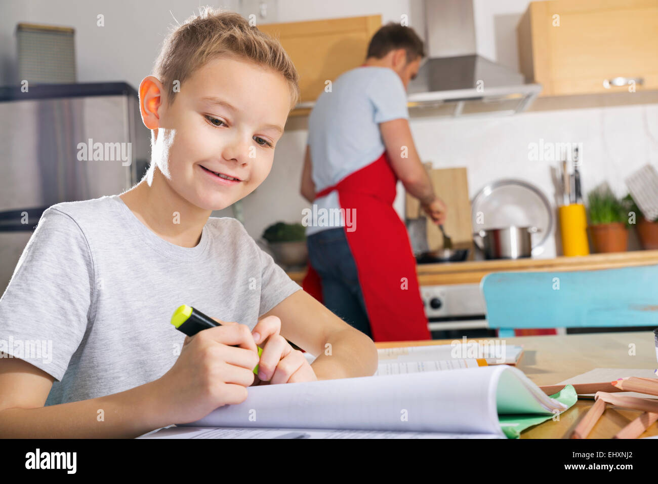 Smiling boy sitting at kitchen table doing his homework Stock Photo - Alamy